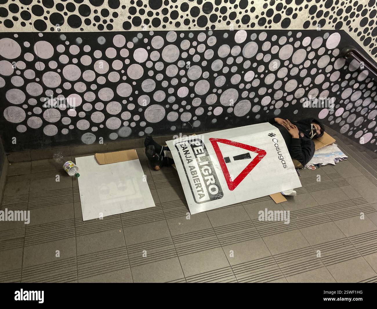 Homeless man sleeping in the entrance of the underground covered with a ...