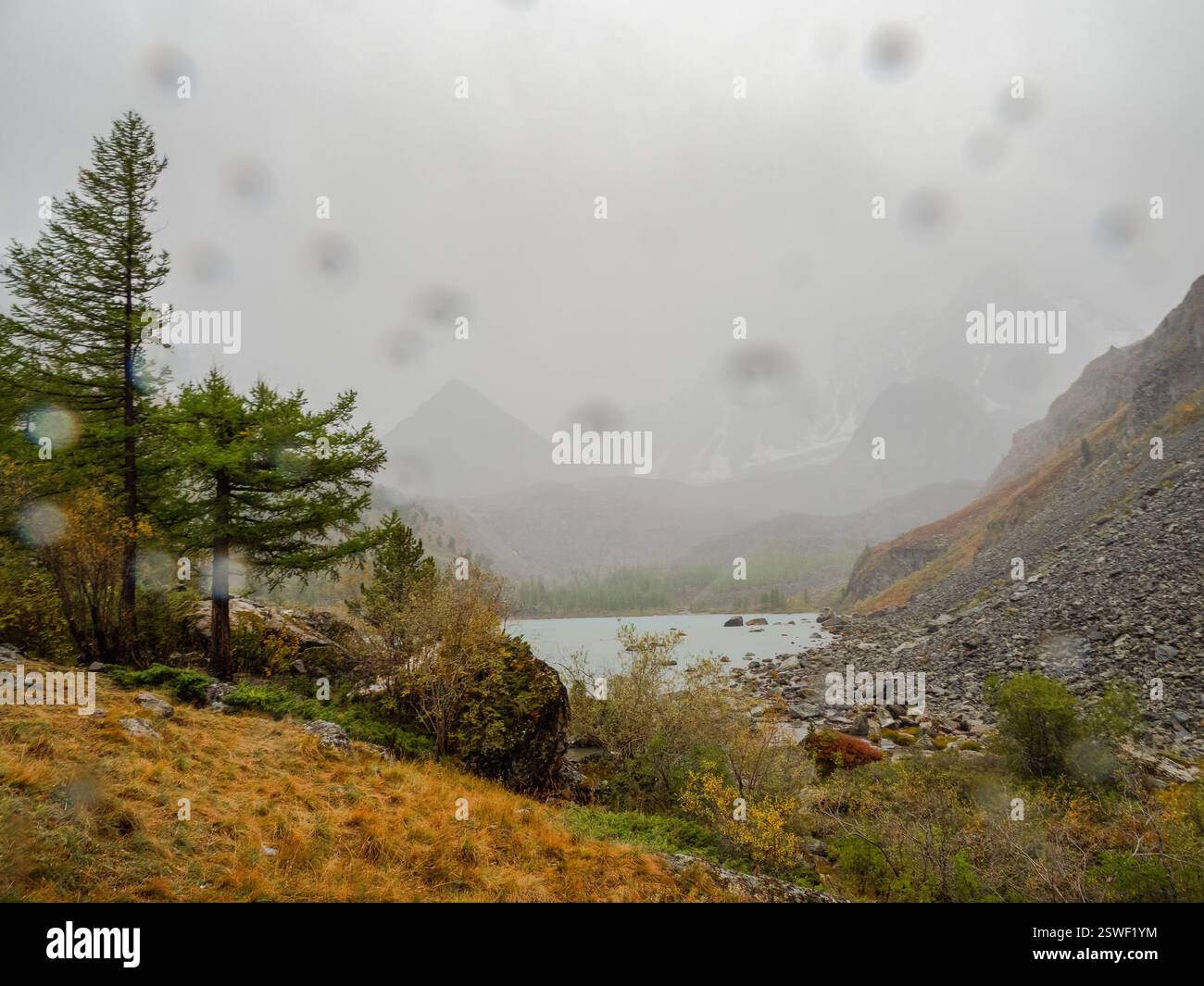 Glass of the camera with drops of rain.Raindrops on mountain lake ...