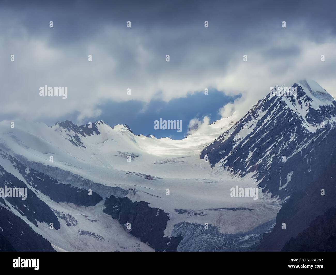 Soft focus. Wonderful minimalist landscape with big snowy mountain peaks above low clouds ...