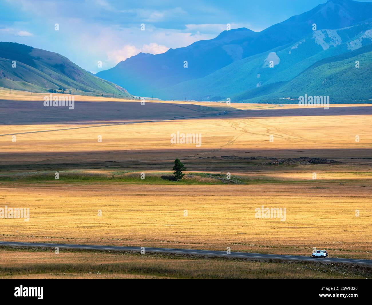Narrow field road with lonely motion car leading through an dramatic ...