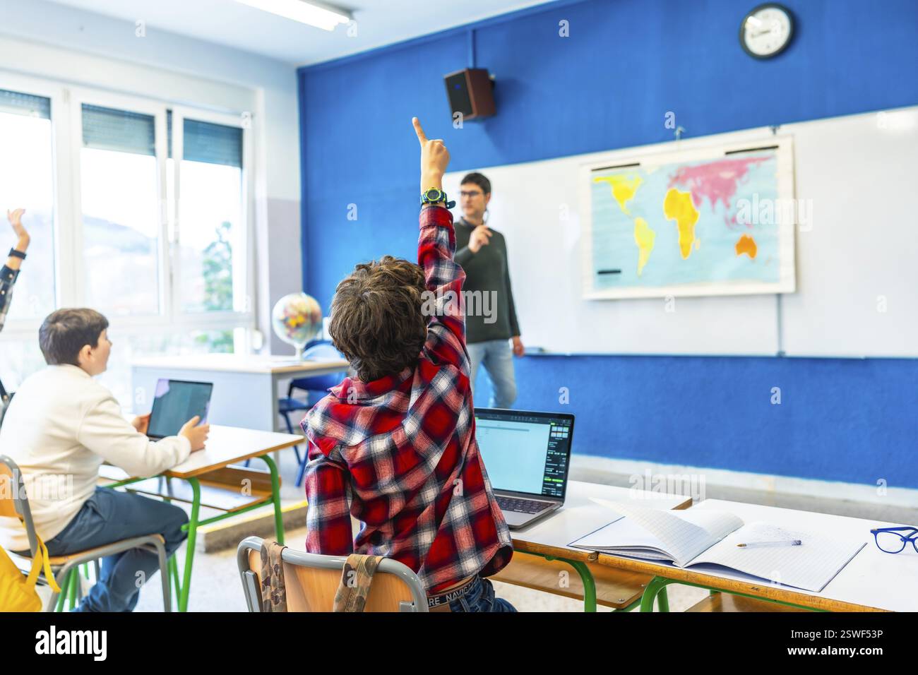 Elementary school student raising hand to answer a question in ...