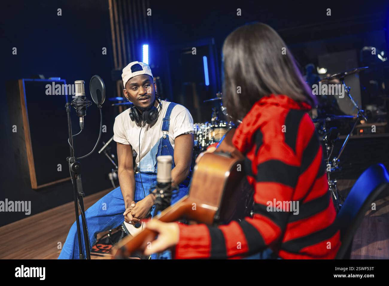 Two musicians collaborating on a new song, playing acoustic guitar and singing into a microphone ...