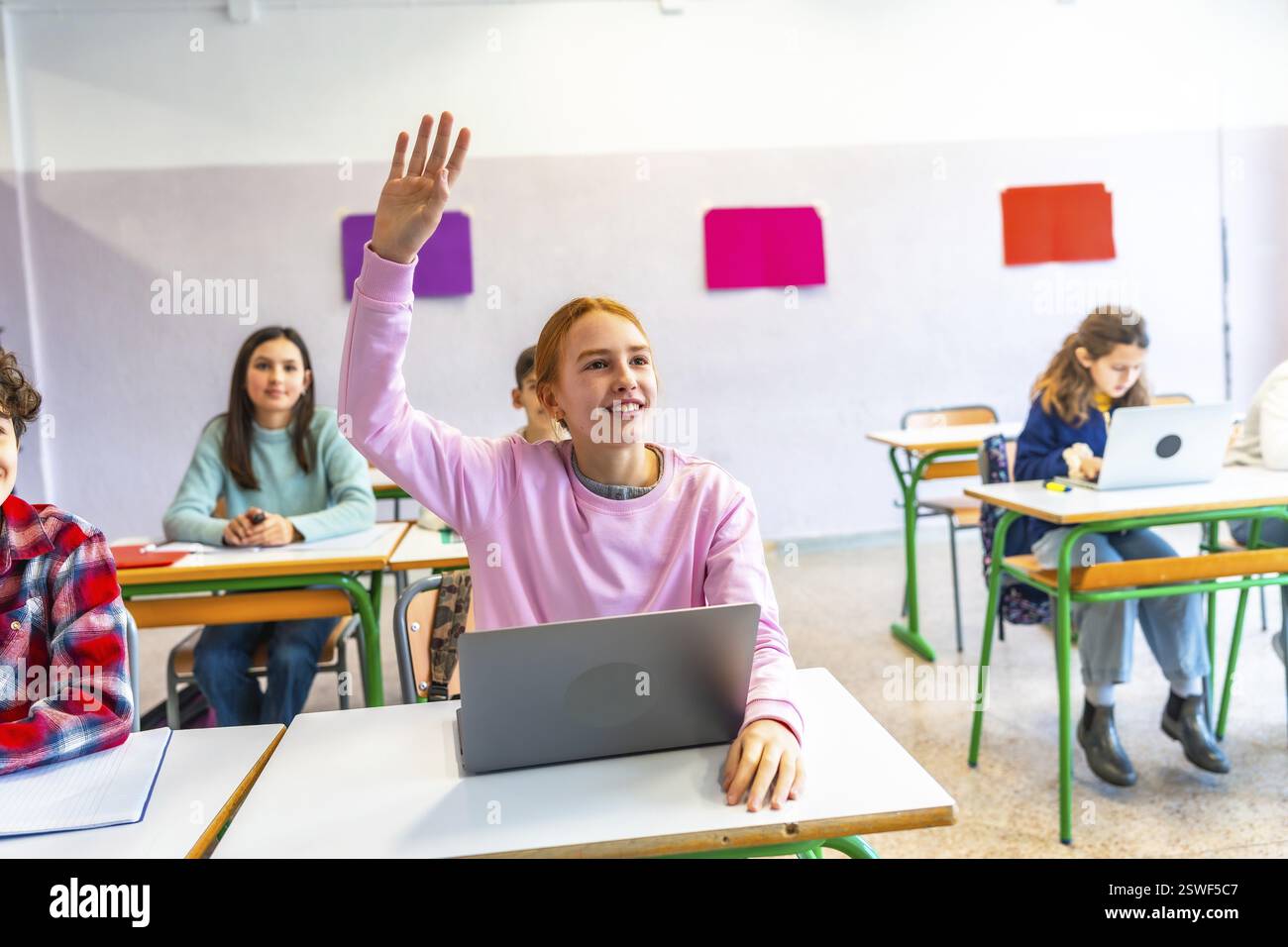 Smart student raises her hand to ask a question during class, showing engagement and ...