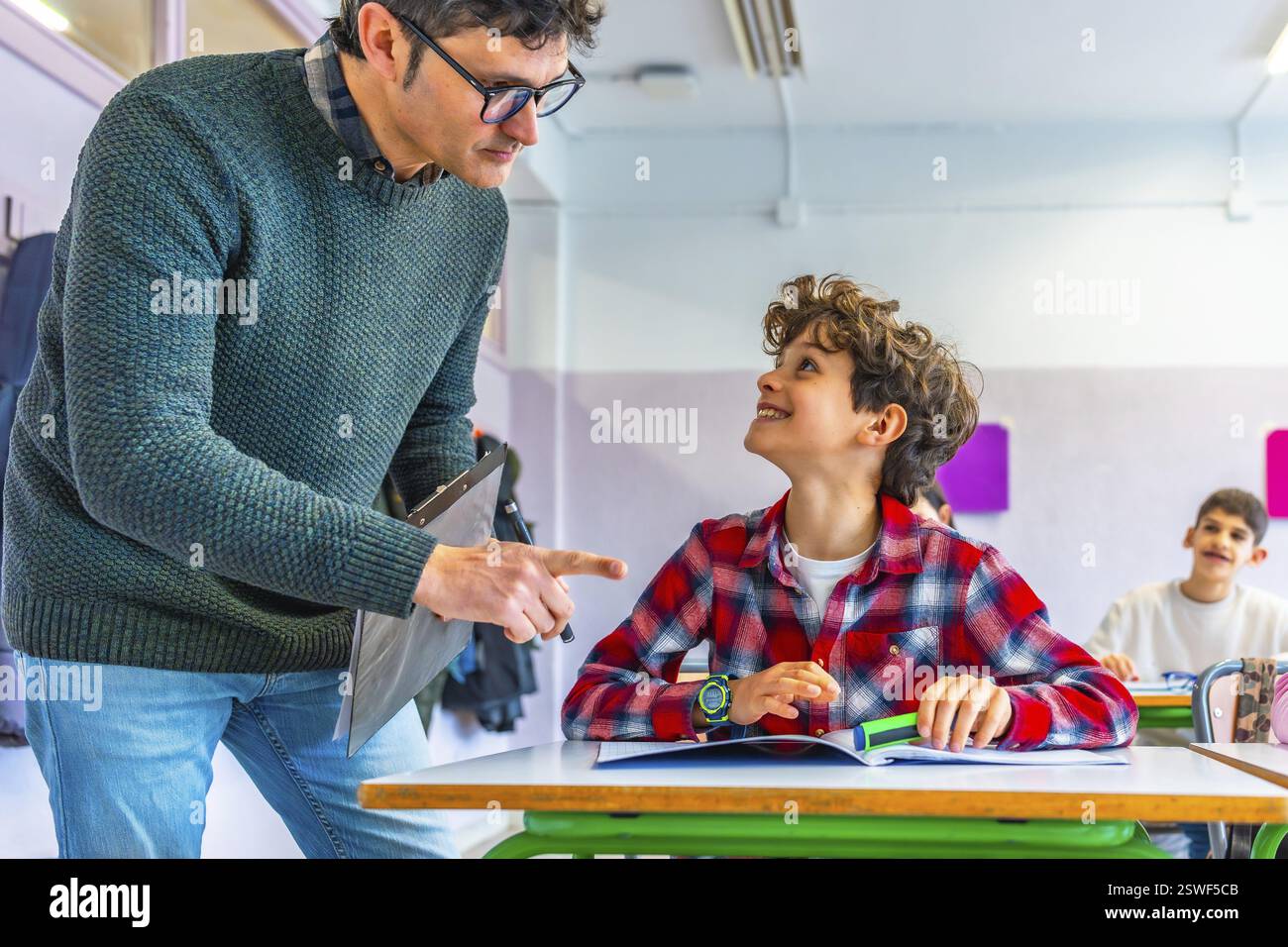 Elementary school teacher engaging with a smiling student while ...