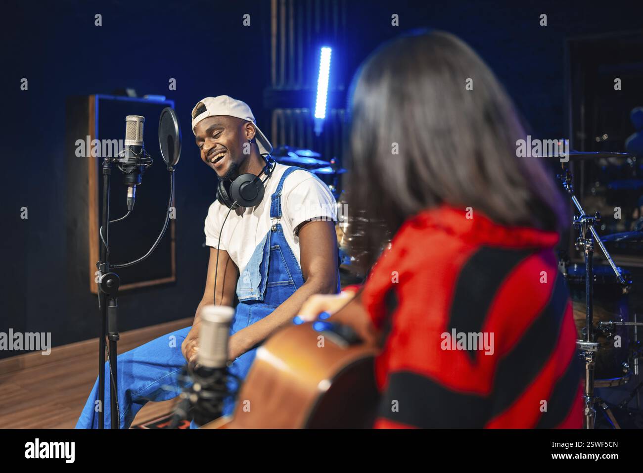Two young musicians recording a song in a professional music studio ...