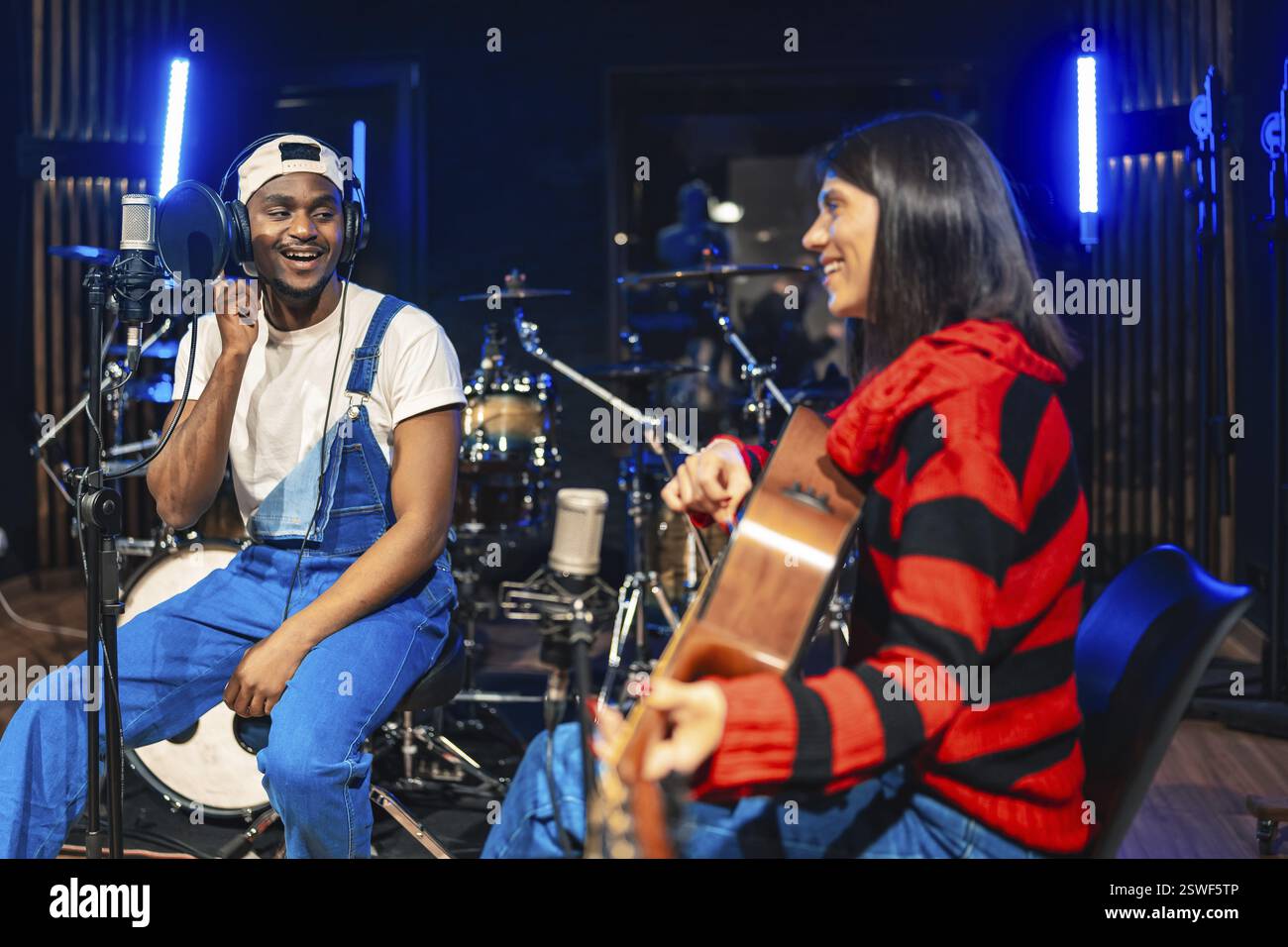 Two musicians playing guitar and singing, recording a new hit song in a ...