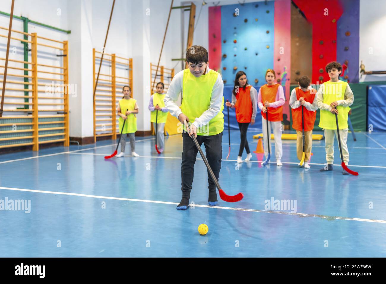 Group of preteen students wearing bibs, actively playing floorball ...