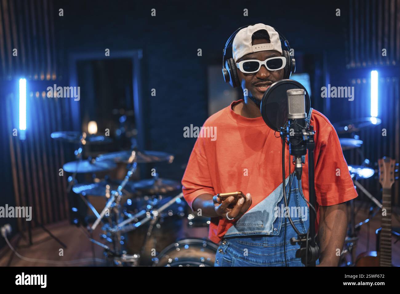 Young stylish male singer recording a new song in a professional ...