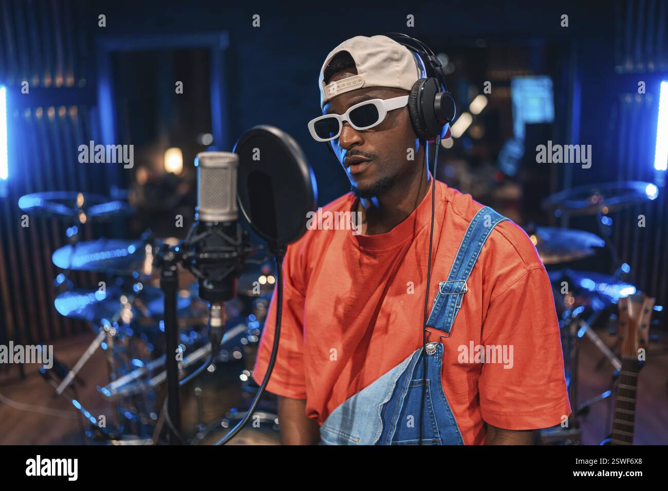 Young, stylish male singer passionately recording a song in a ...