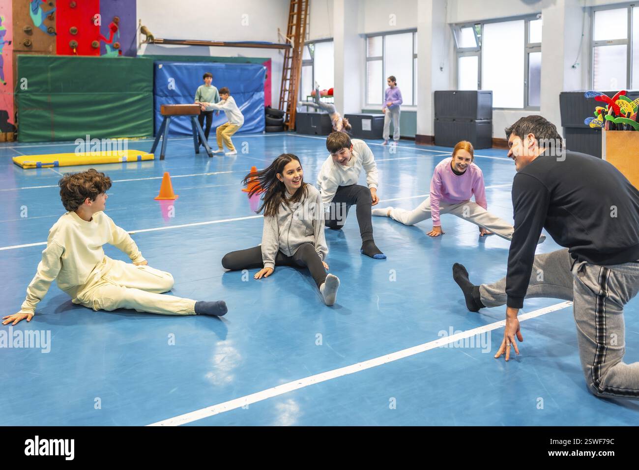 Group of smiling students practicing stretching exercises with their ...