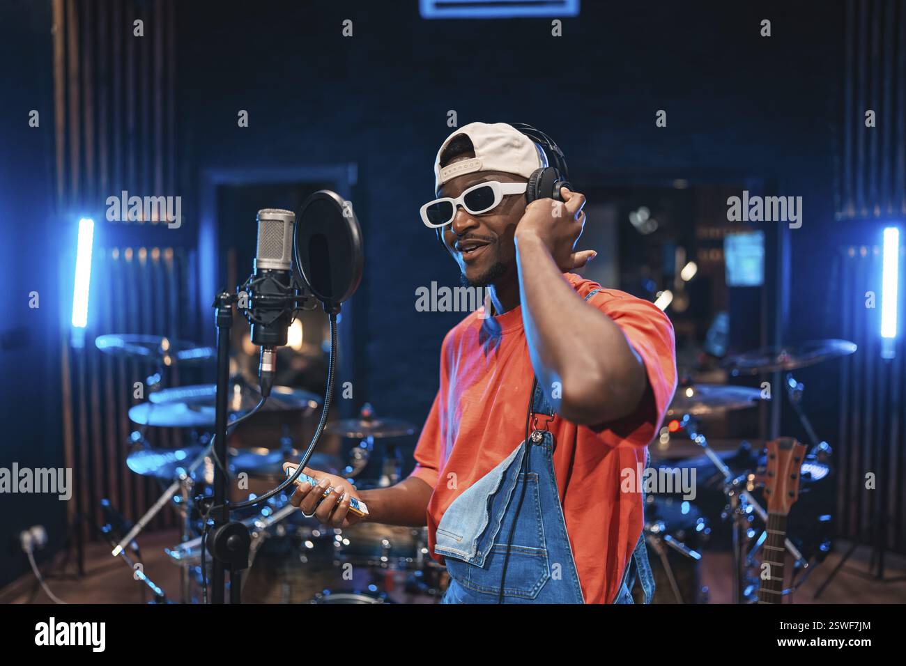 Talented musician wearing trendy clothes, holding smartphone and ...