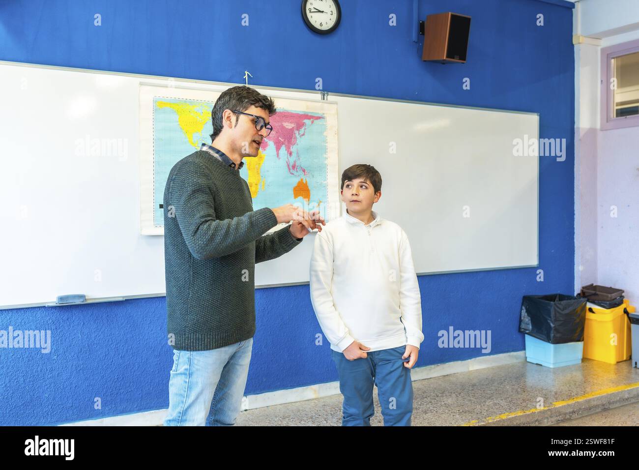 Geography teacher explaining lesson to elementary school student using ...