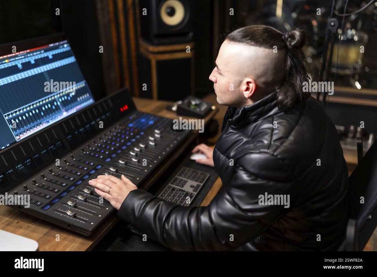 Young man mixing music on an audio mixing console in a contemporary ...