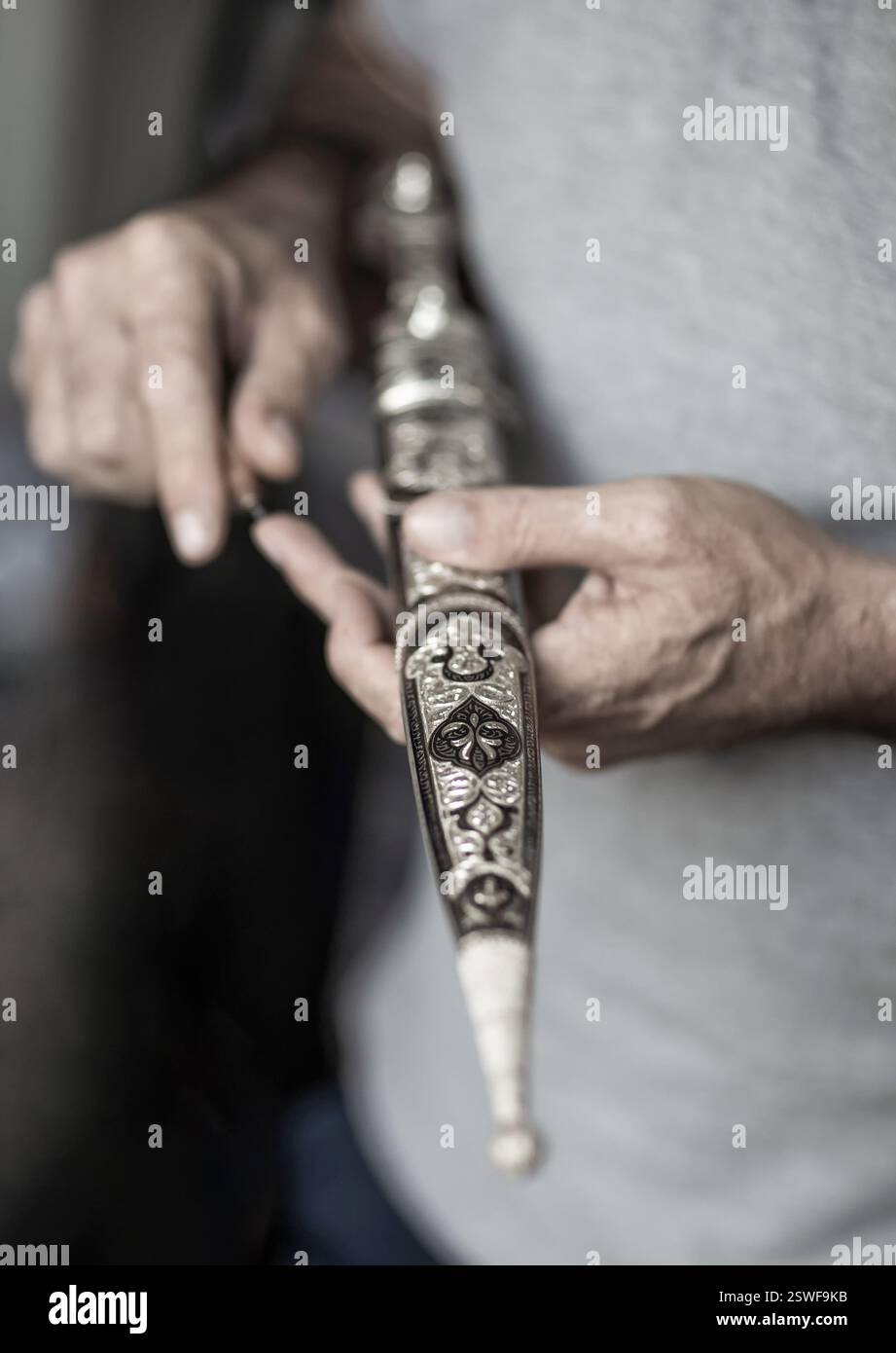 Selective focus. The hands of a dagger maker at work, close-up. Silver ...