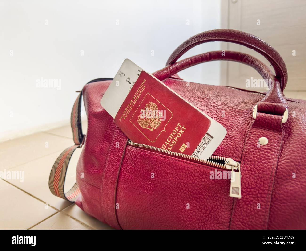 Red Russian passport with airline ticket on touristic red bag close up ...