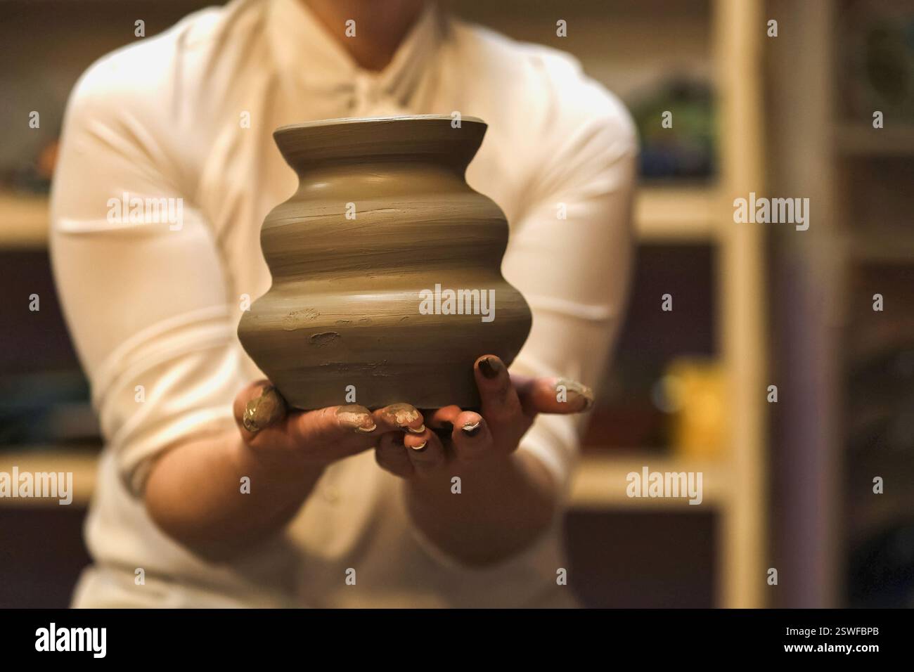 Green ceramic jug in hand close-up. Potter holds just hired by pottery. Ceramic skills. Sculptor ...