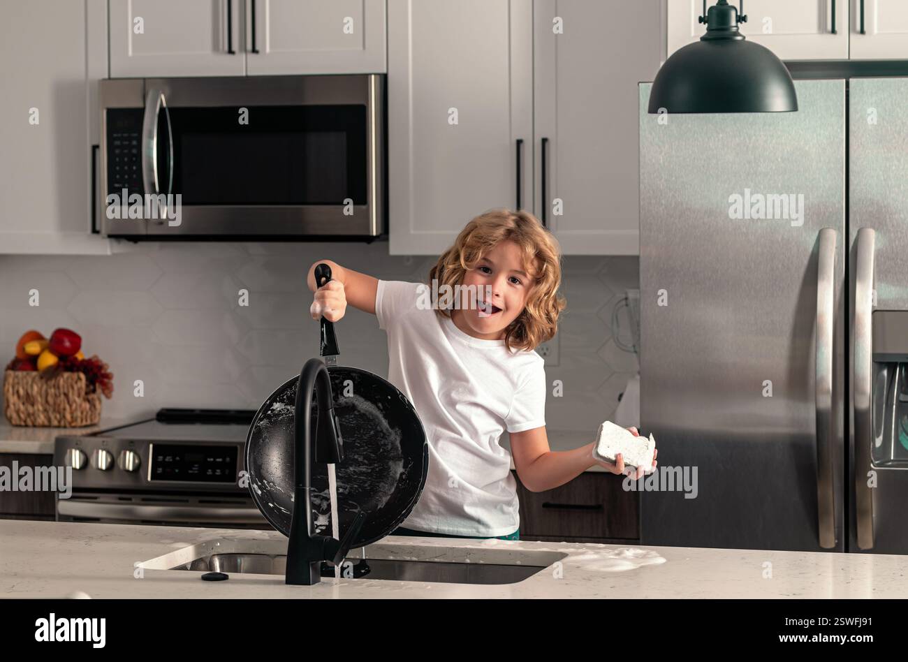 Child housekeeper washing the dishes on soapy water. Cute Funny boy ...