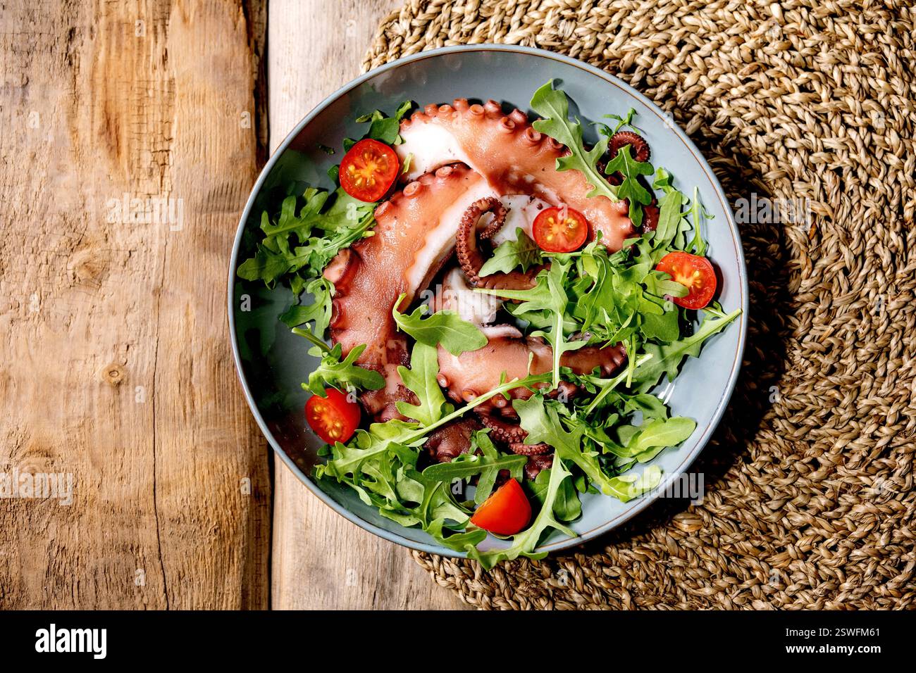 Seafood salad. Coocked tentacles of octopus on blue ceramic plate ...