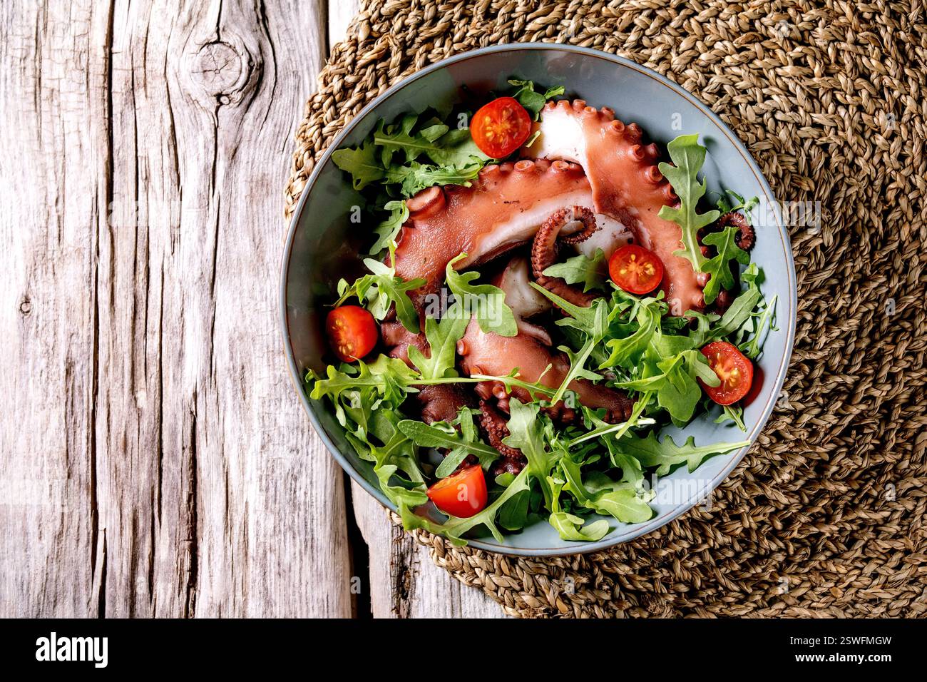 Seafood salad. Coocked tentacles of octopus on blue ceramic plate ...