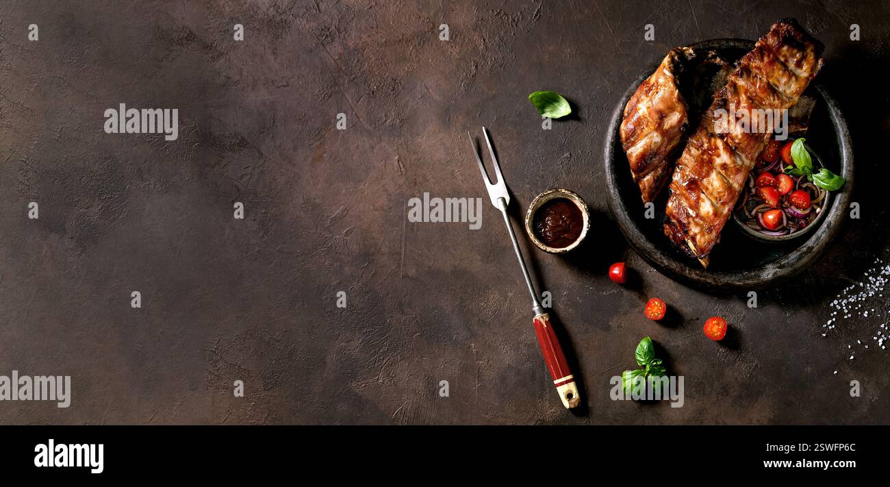 Grilled pork bbq ribs in ceramic plate served with meat fork, marinated ...