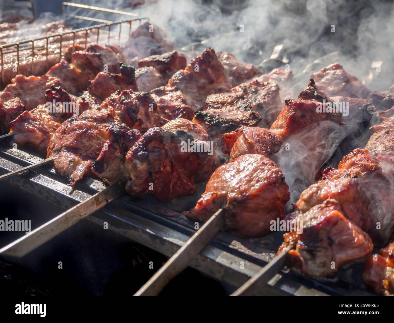 Cooking BBQ meat. Caucasian kebab fried on a grill in the smoke at the ...
