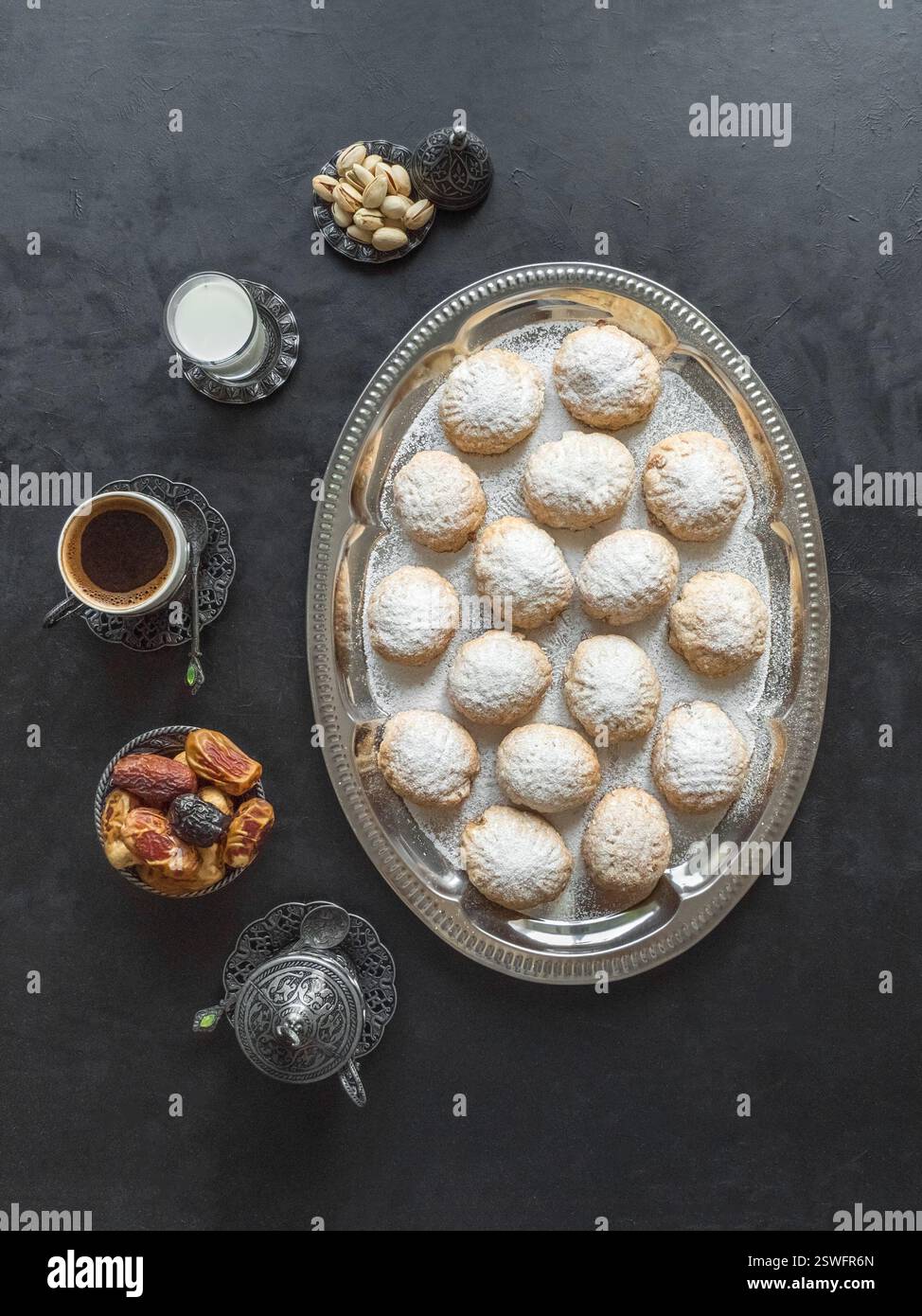 Festive Ramadan sweets are served with tea on the black table. Egyptian ...