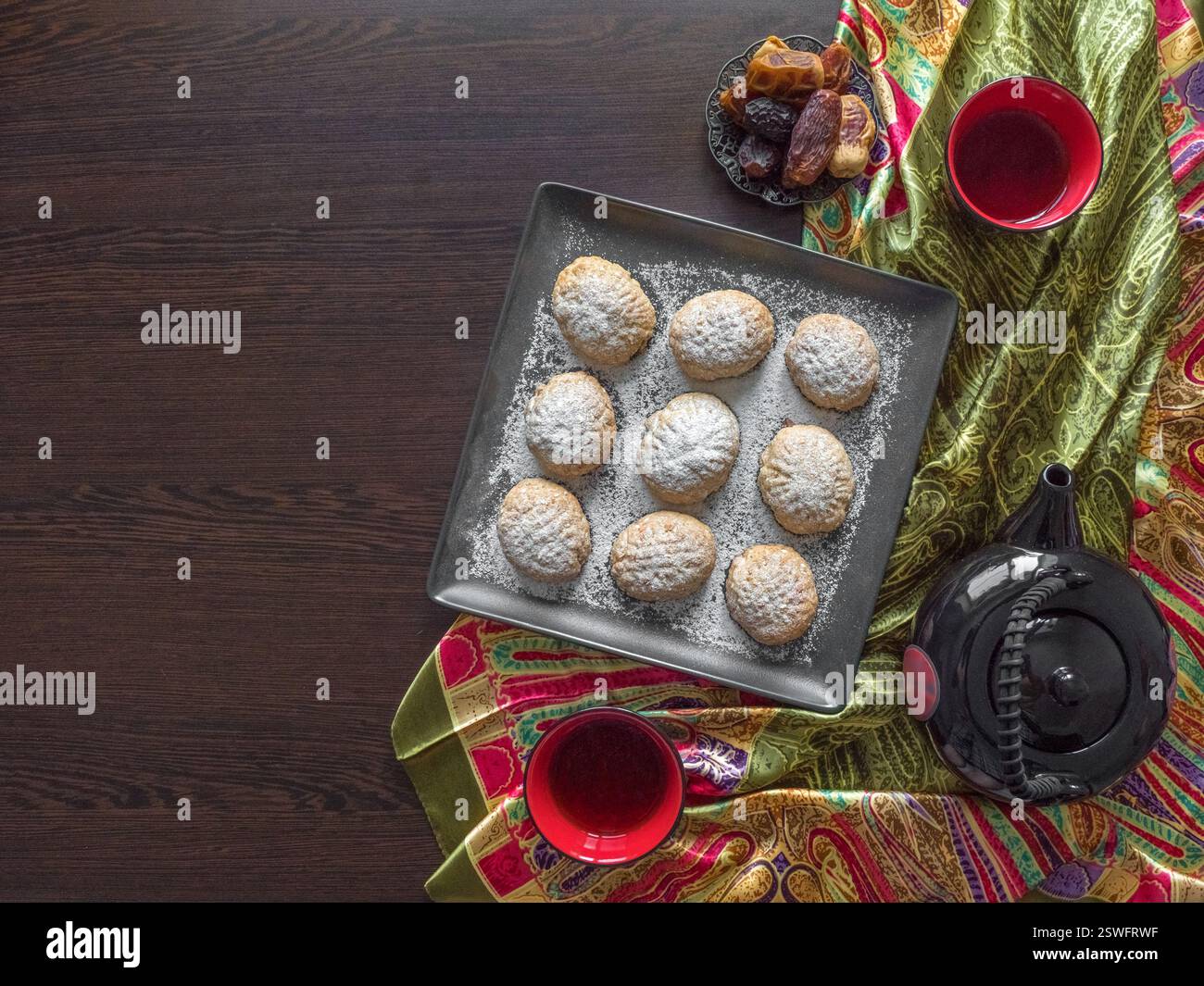 Handmade Ramadan sweets are served with tea on the dark wooden table ...