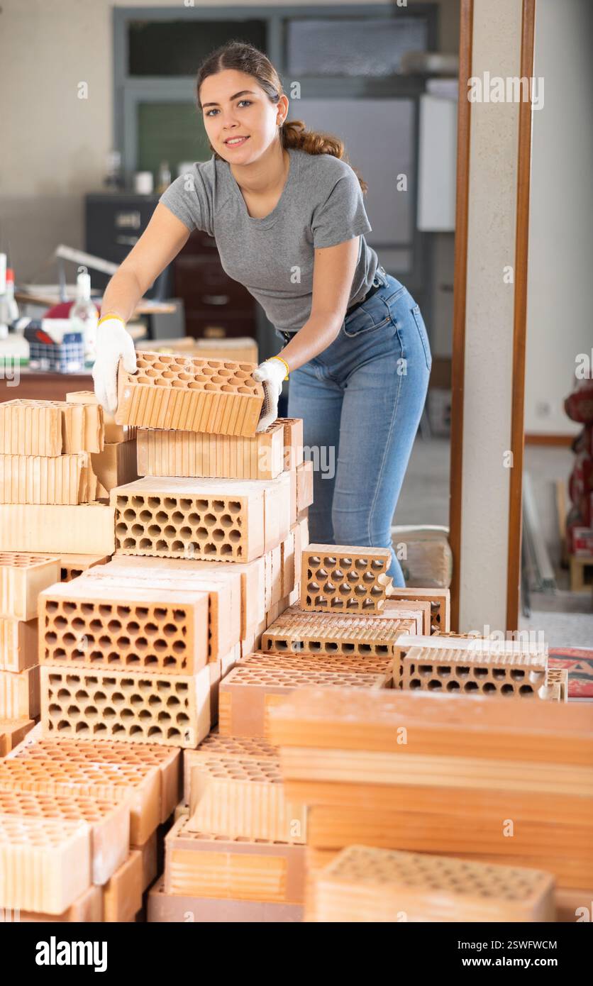 Young woman stacking bricks in building site Stock Photo - Alamy