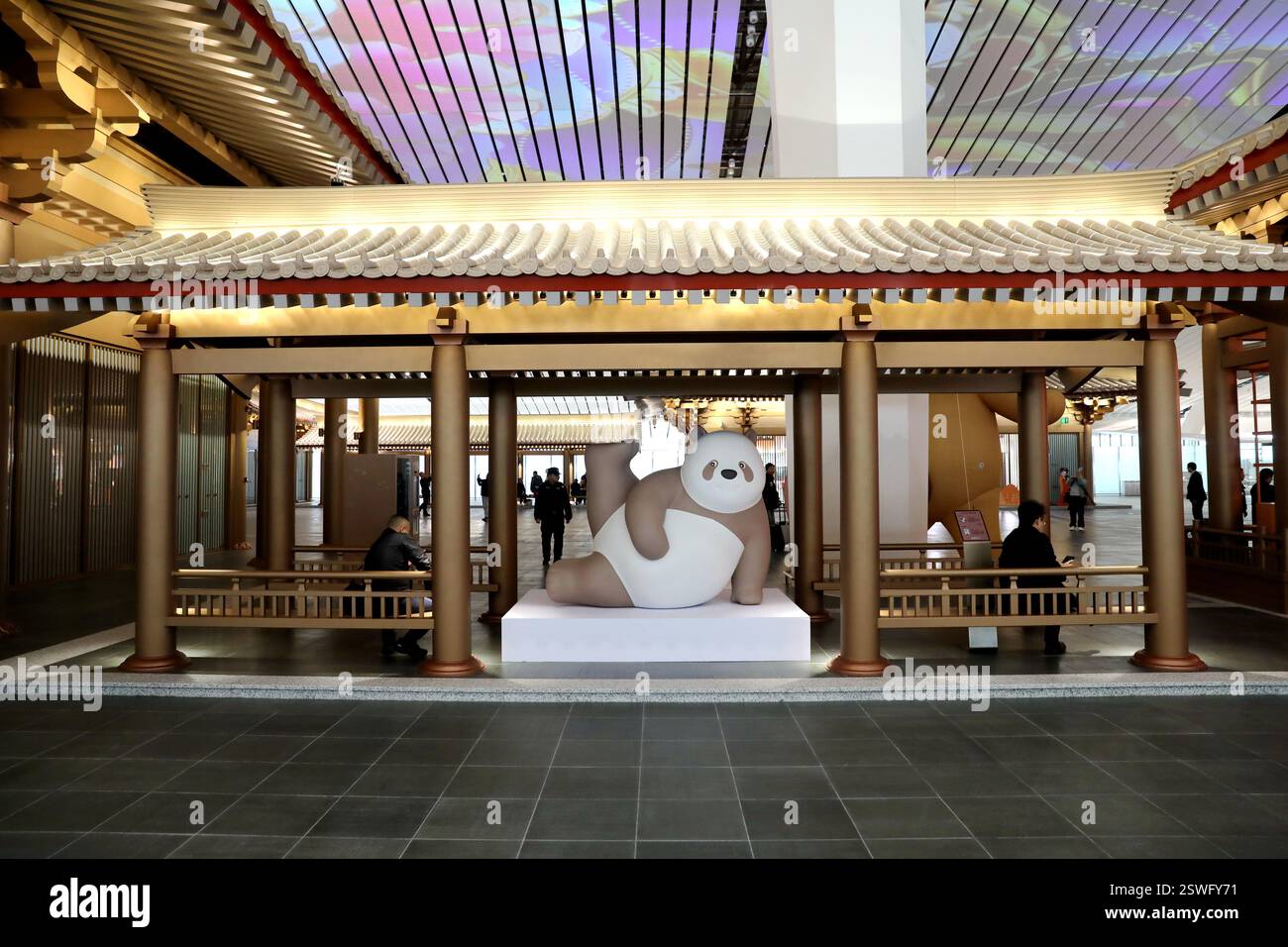Xi'an,China.20th February 2025. Passengers rest next to a sculpture of ...