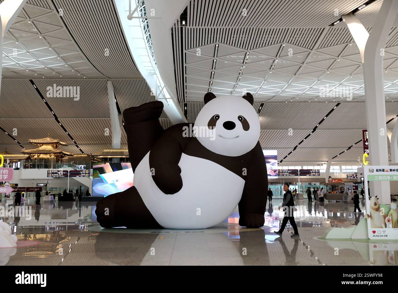Xi'an,China.20th February 2025. Passengers walk past a sculpture of ...