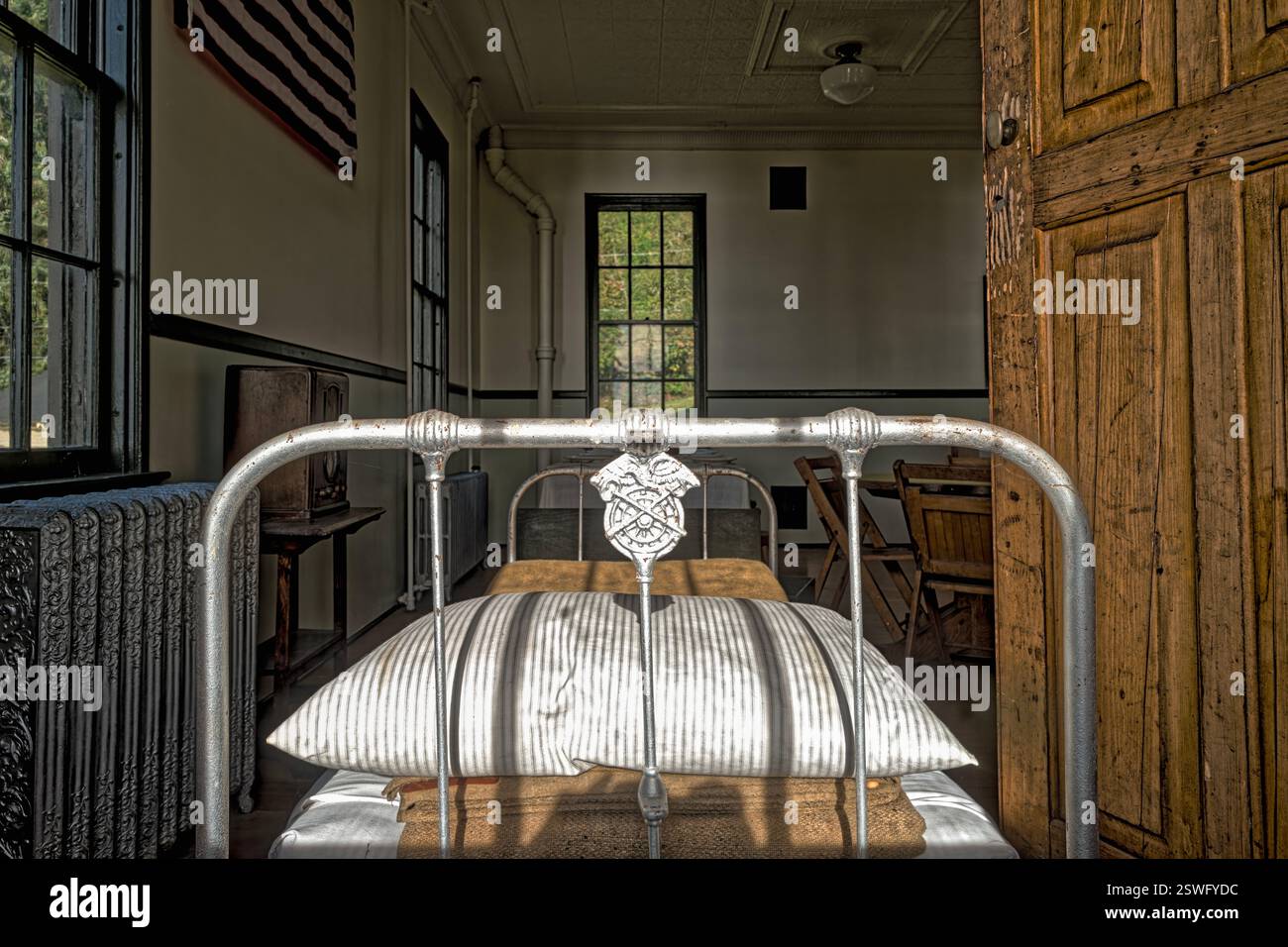 The sun shines through a window on a bed in an abandoned military ...