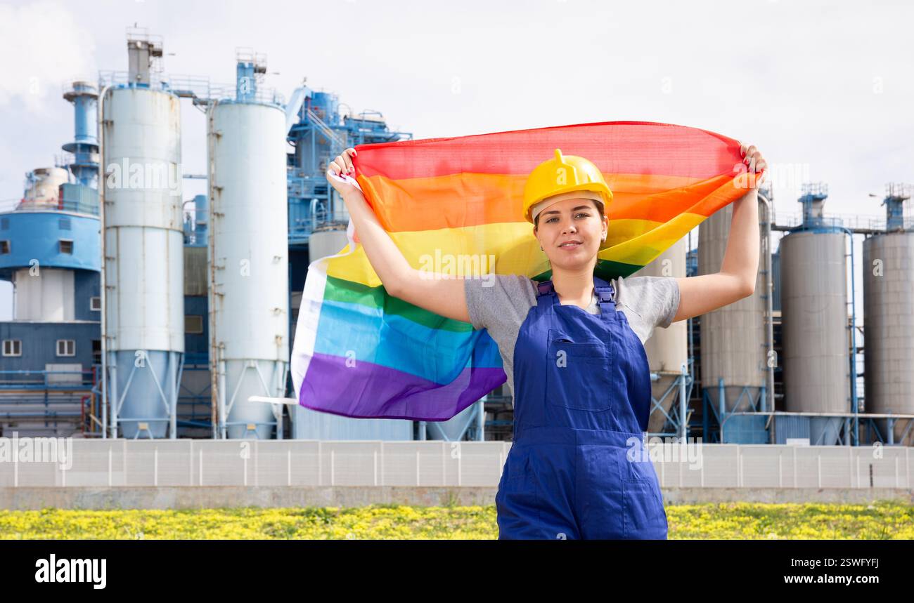 Woman in blue overalls waving the flag of LGBT against backdrop of ...