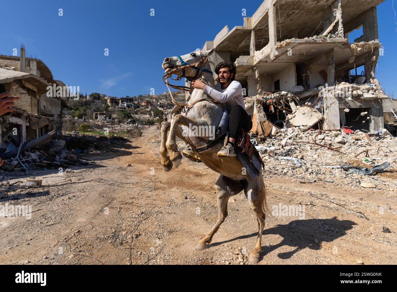A Lebanese man rides his horse in a village destroyed by an Israeli air ...