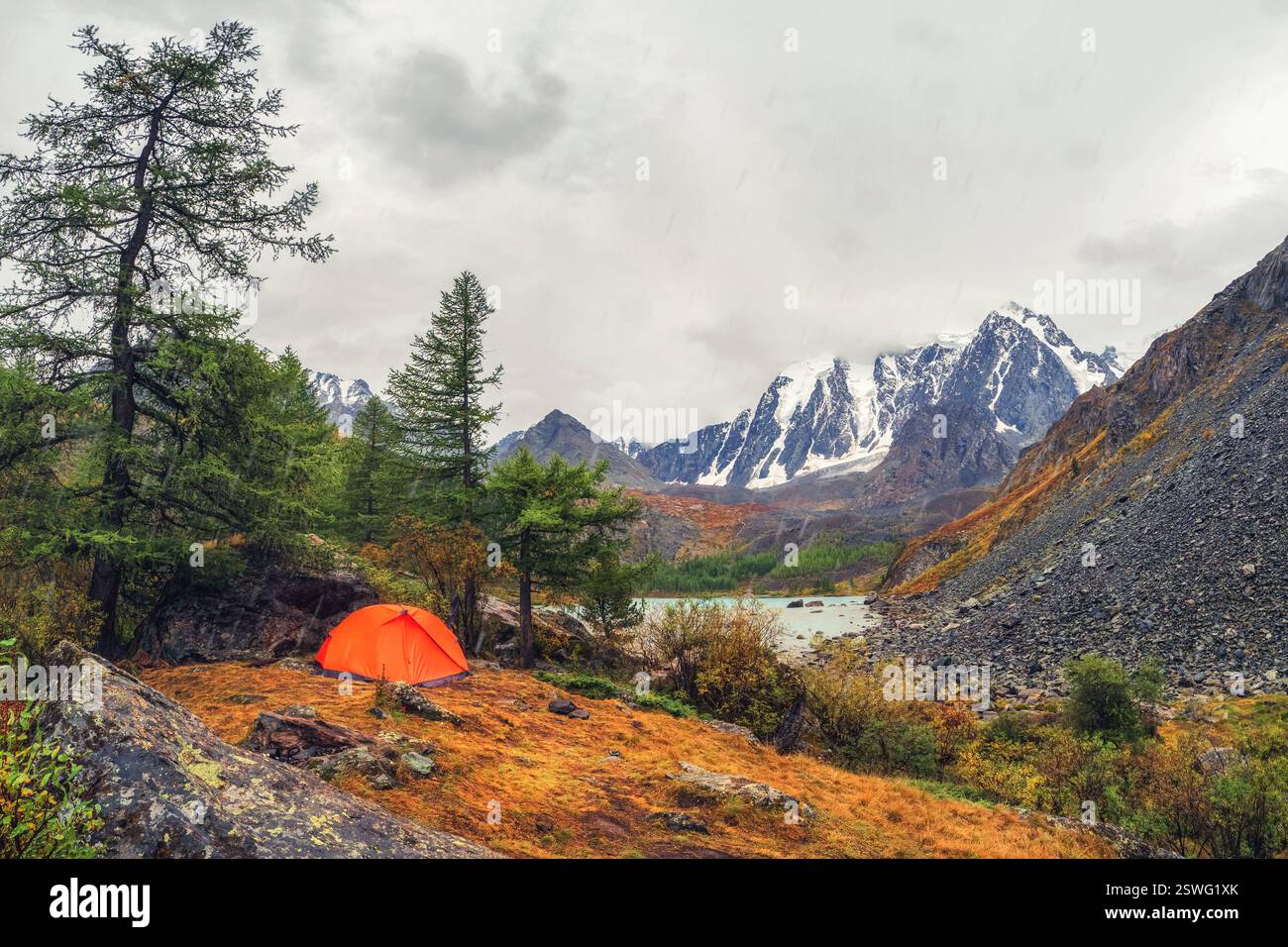 Camping on a autumn high-altitude plateau. Orange tent under the rain ...
