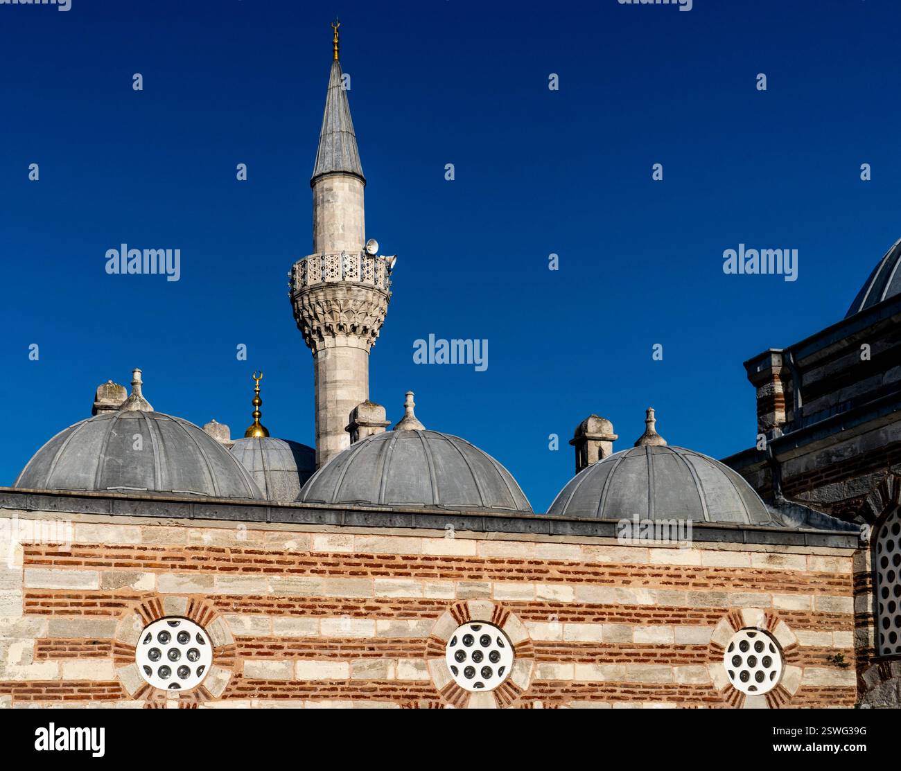 A close-up view of a mosque featuring domes and a tall minaret against ...
