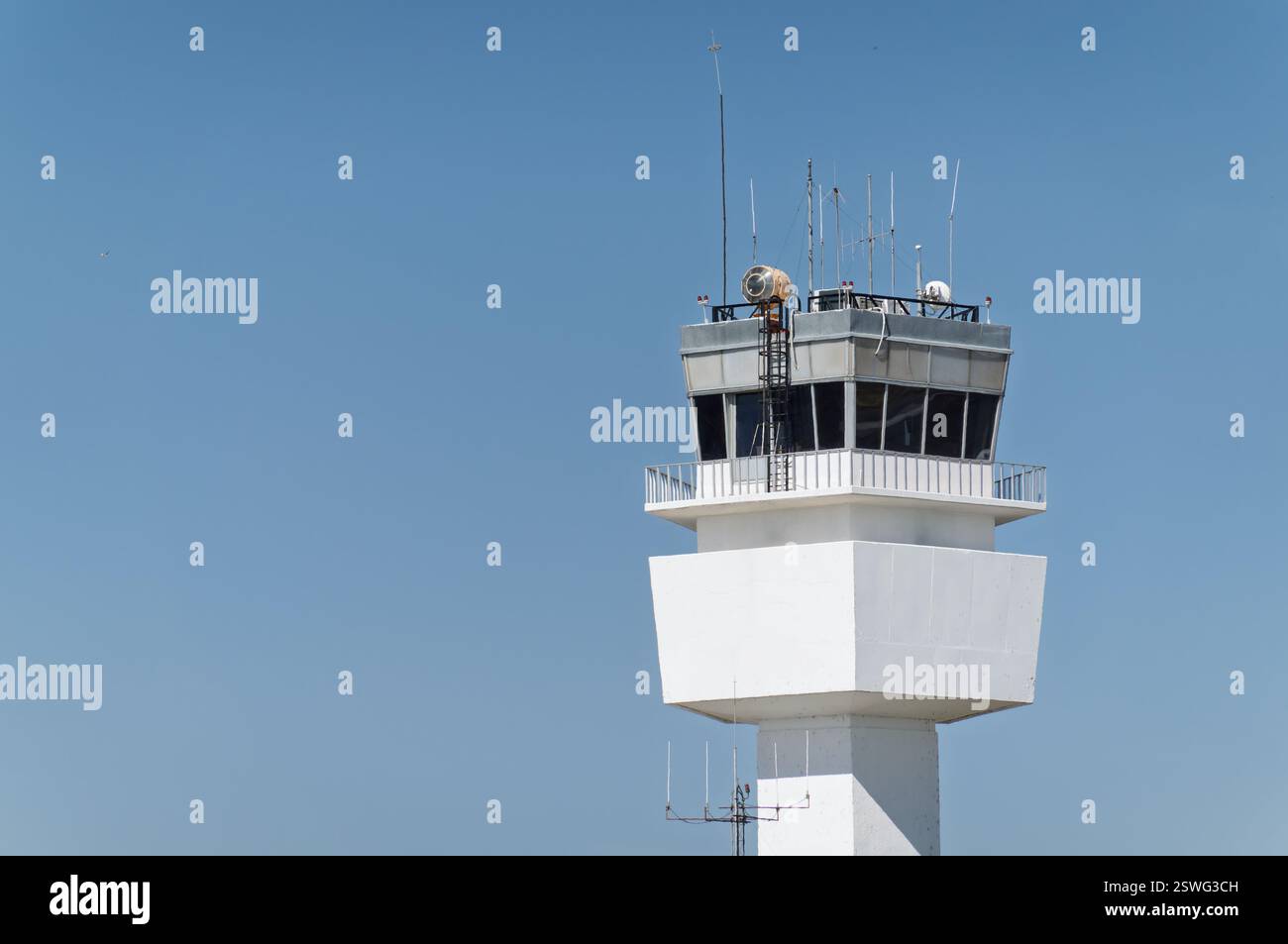 A detailed view of a white air traffic control tower with antennas ...