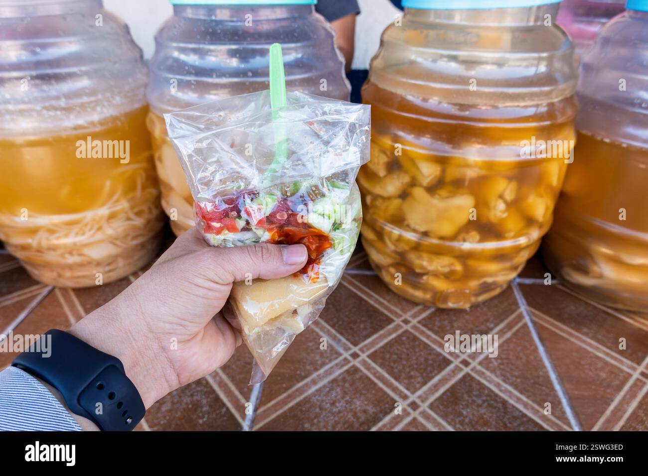 Close-up of a hand holding a bag with pickled pork trotter, lettuce ...