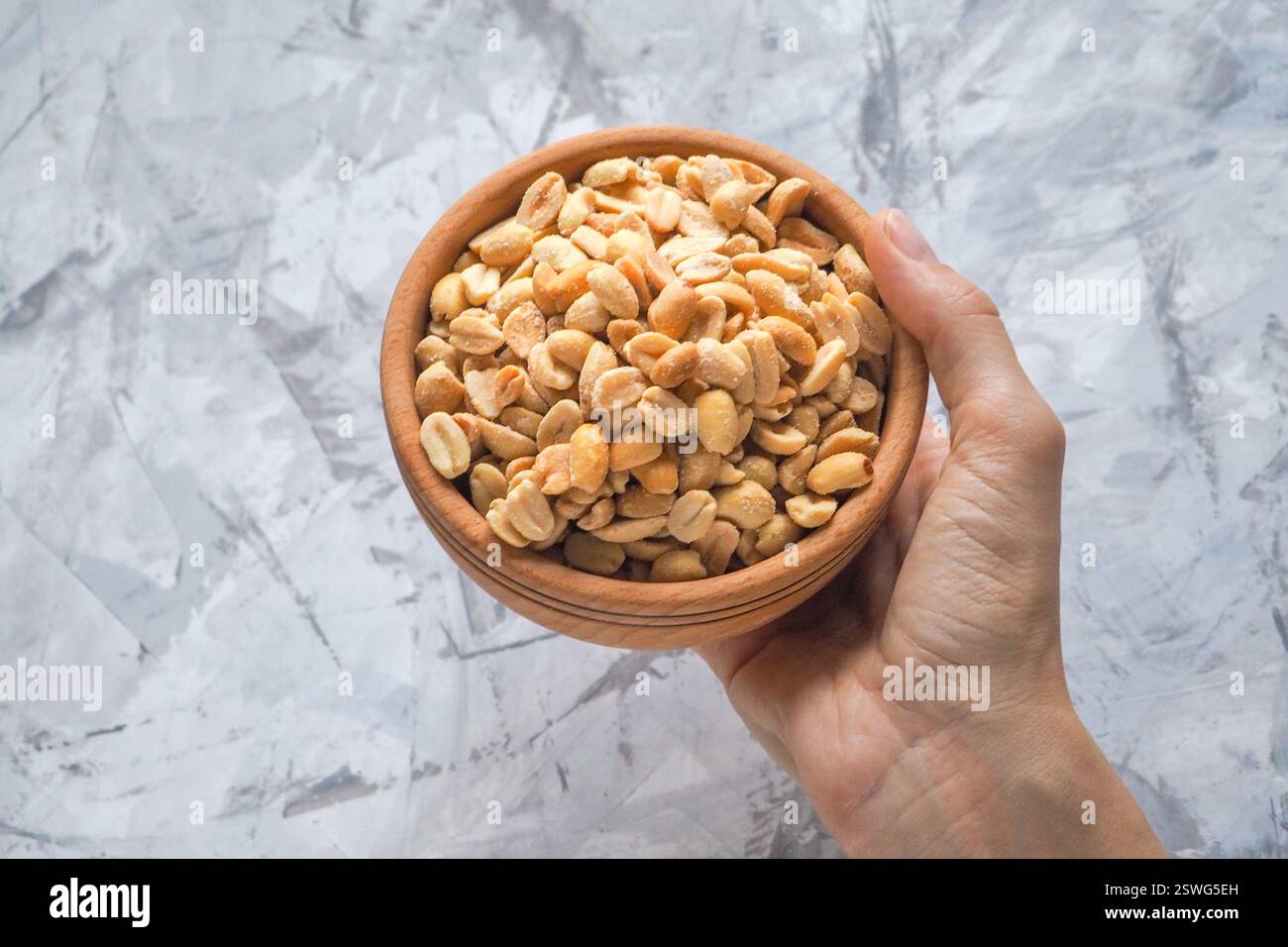 Roasted salted peanuts in hand. Roasted nuts in a bowl Stock Photo - Alamy