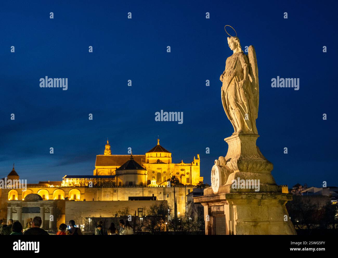 Statue of Saint Raphael at dusk on the Roman Bridge of Cordoba with ...