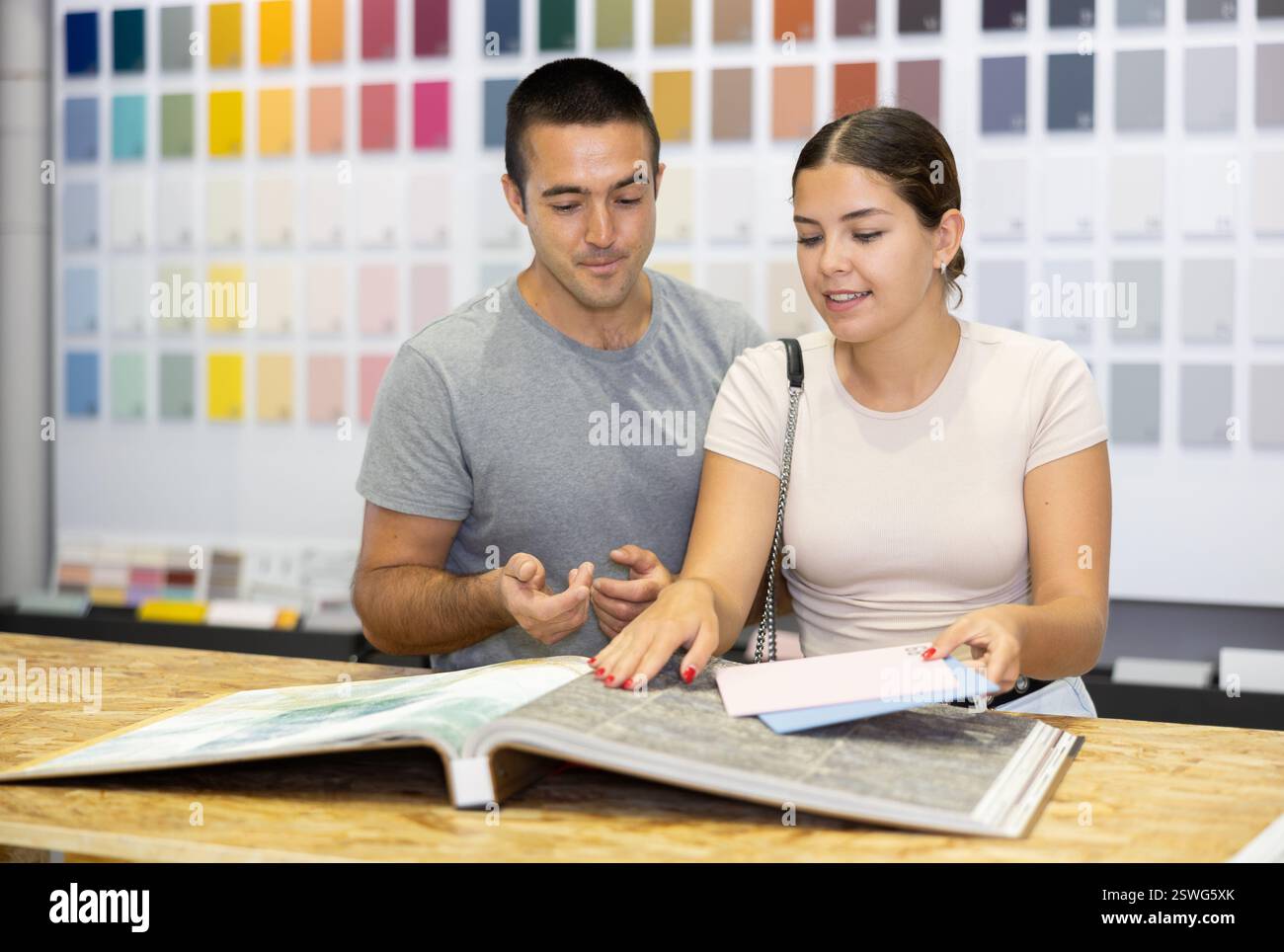 Positive couple flipping through paint color catalog and discussing in ...