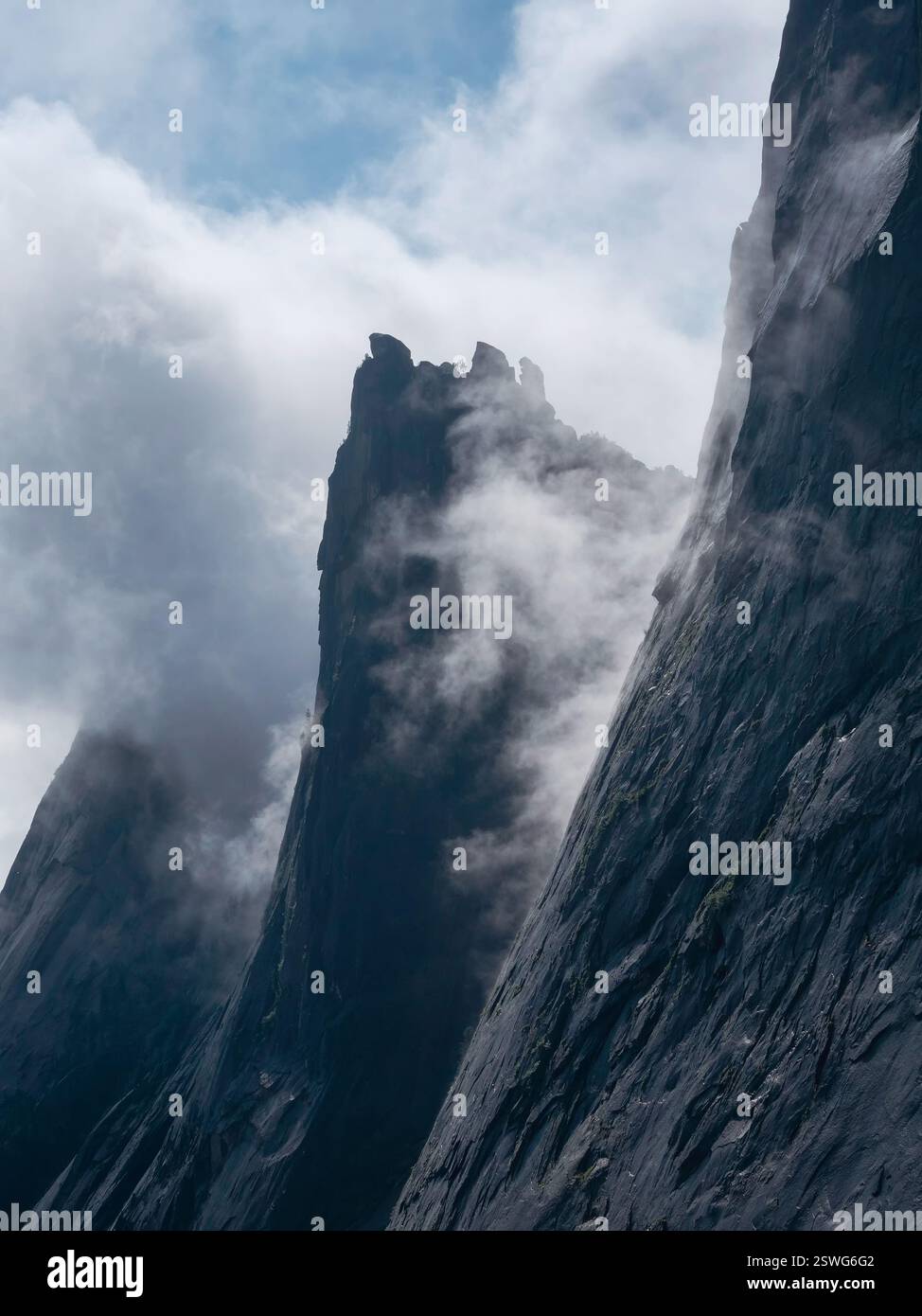 Vertical view of great mountains in the fog. Low clouds and dark peaks ...