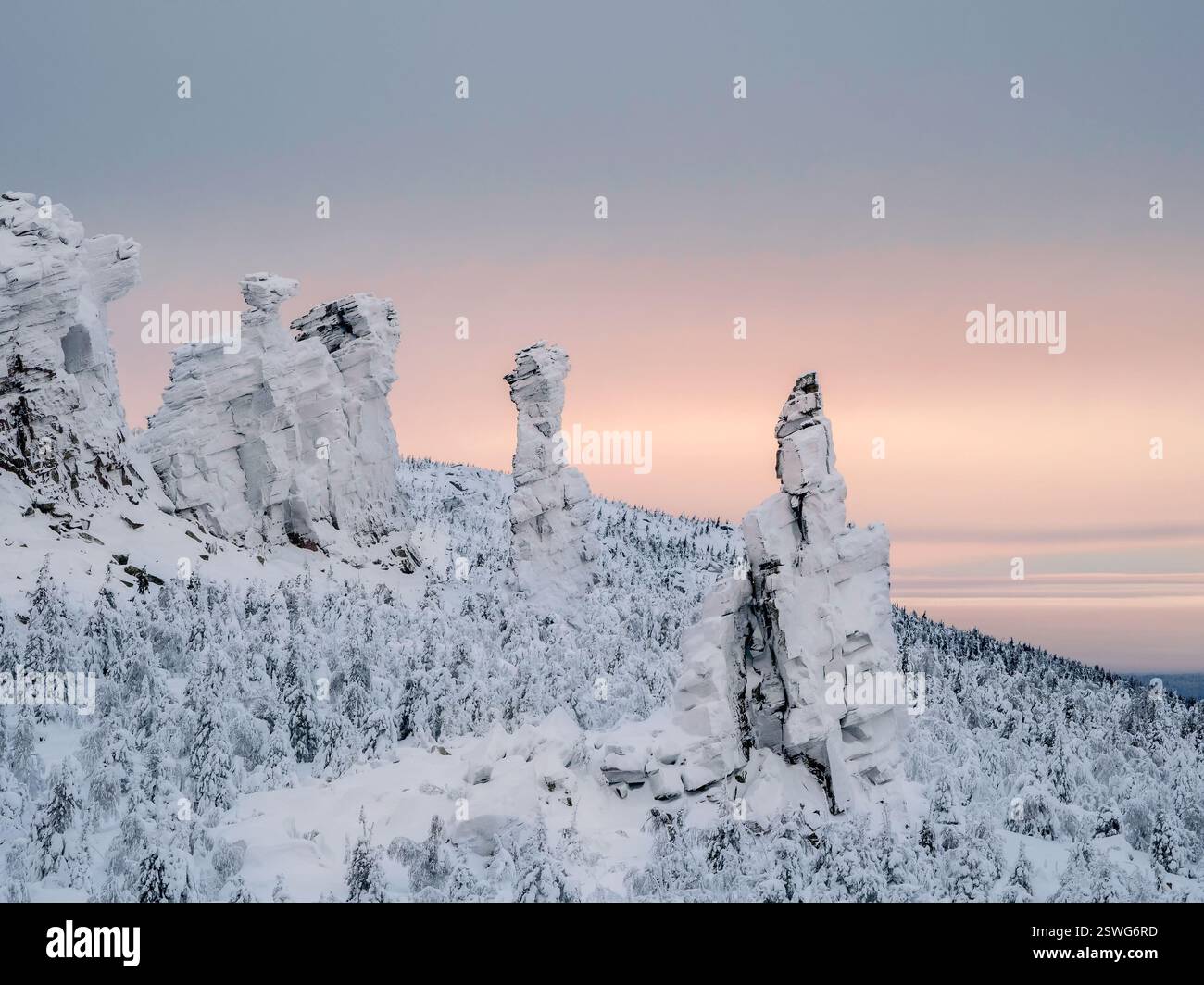 Mystical dawn in the snow-covered mountains. Rock pillars, weathering ...