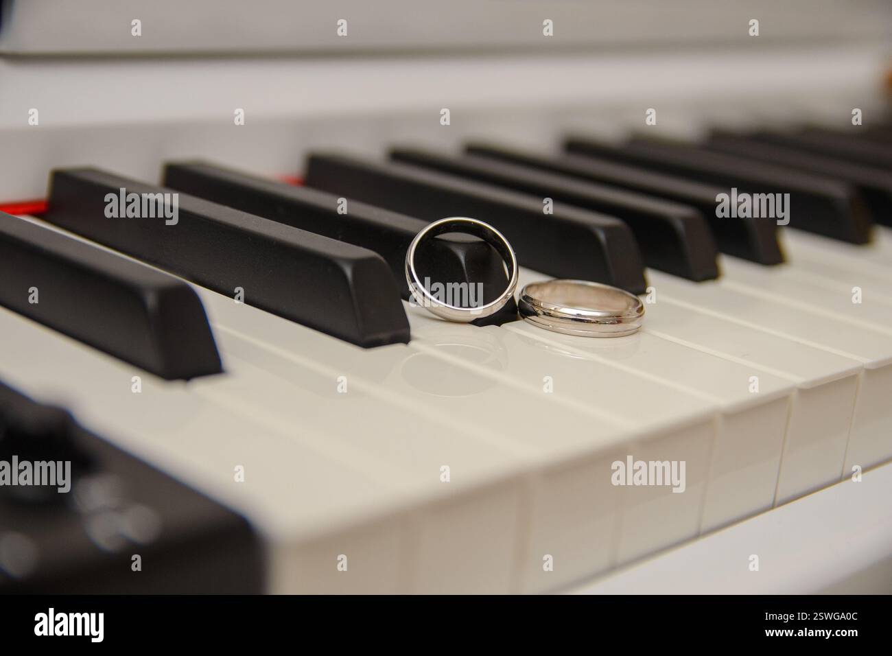 Two white gold wedding bands set on piano keys Stock Photo - Alamy