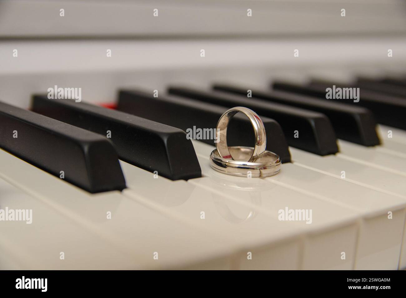 Two white gold wedding bands set on piano keys Stock Photo - Alamy