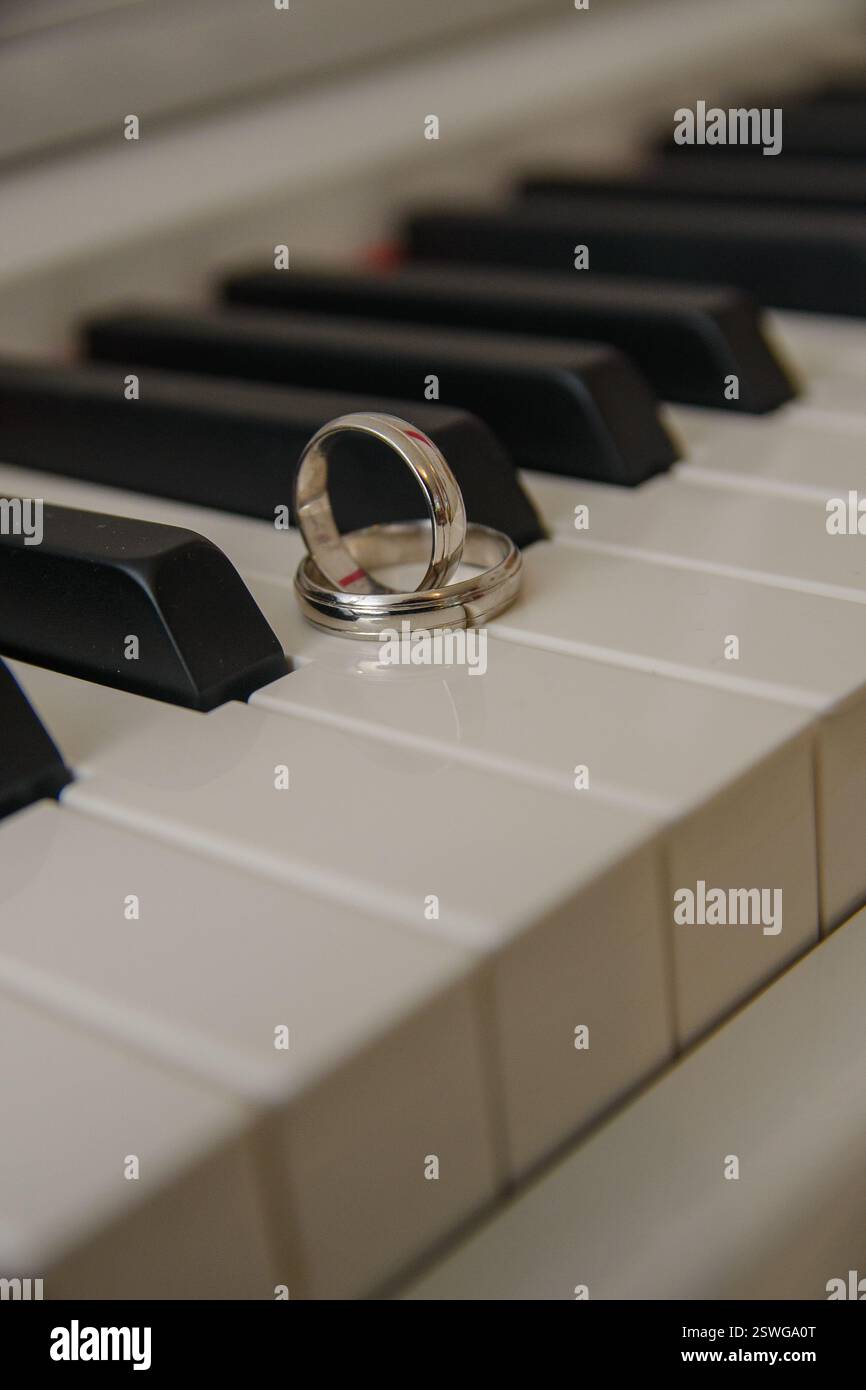 Two white gold wedding bands set on piano keys Stock Photo - Alamy