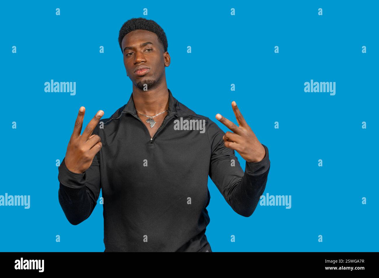 Confident young man gesturing peace sign with both hands on a vibrant ...