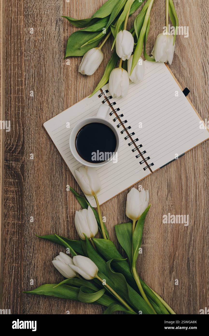 Cup of Coffee, open book and a bouquet tulip flowers over wood table ...