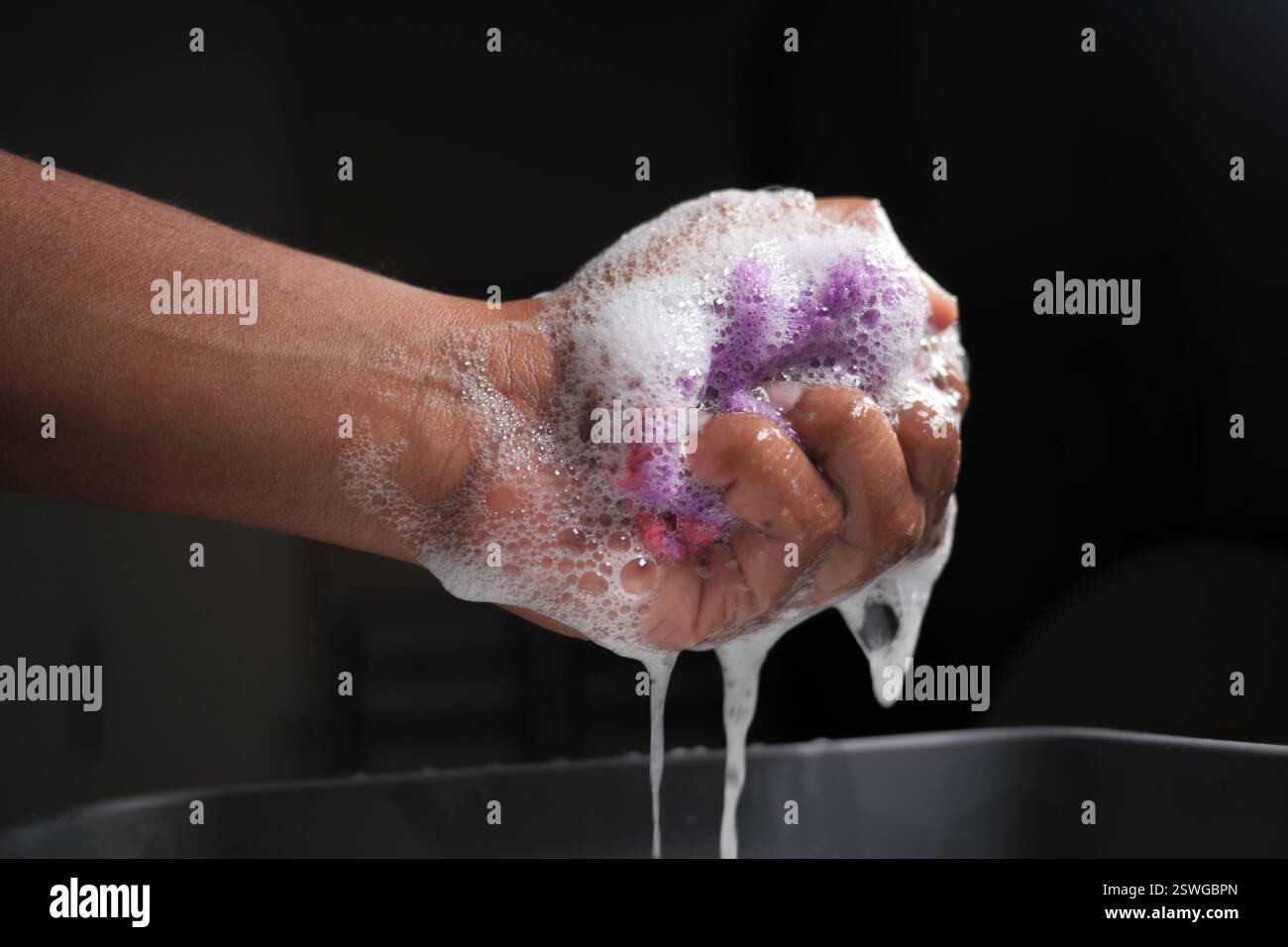 Hand washing a soapy sponge over a container of water Stock Photo - Alamy