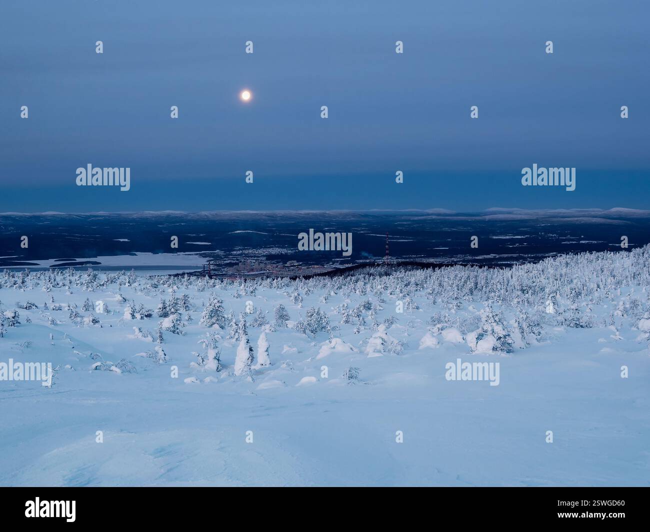 Full moon over the snow-covered slope of the polar hill in winter with ...