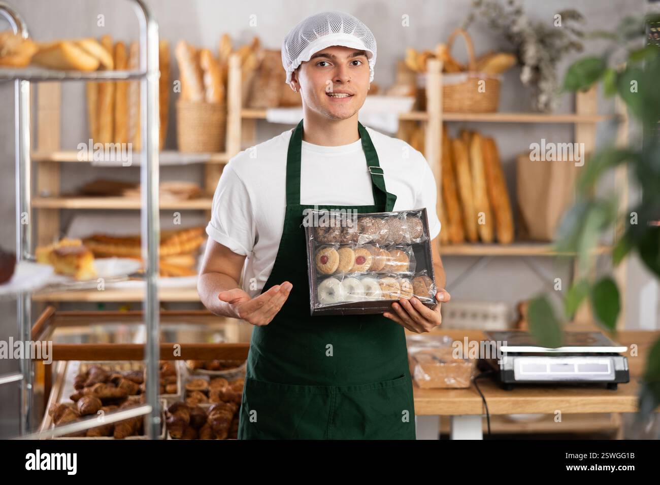 Young man entrepreneur owner of bakery holds out cardboard box with ...